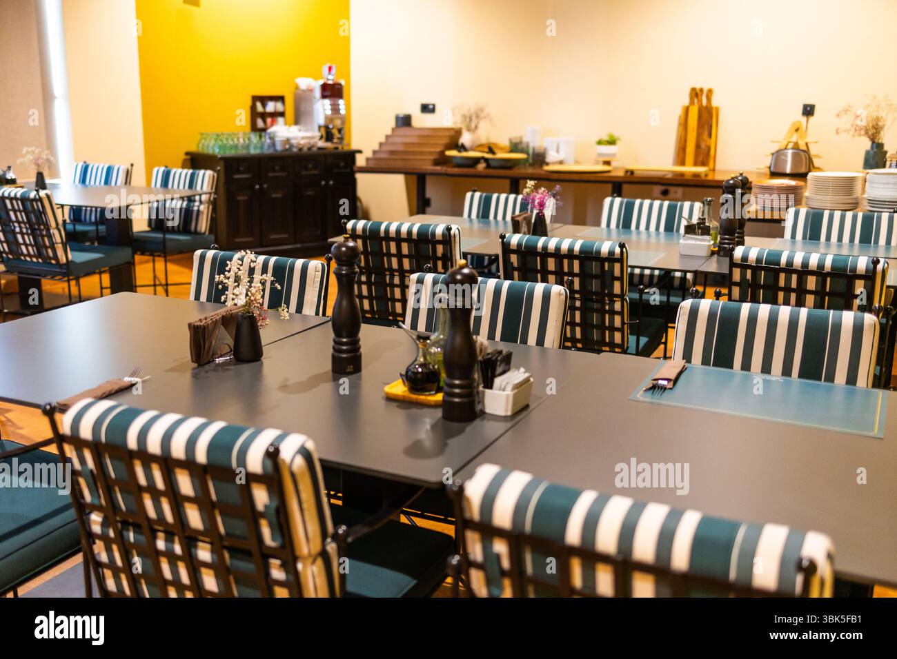 Modern hotel breakfast room with striped chairs and buffet area. Cozy ...