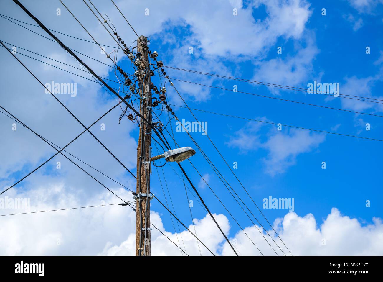 Old wooden lamp post with street light and messy electrical wires ...