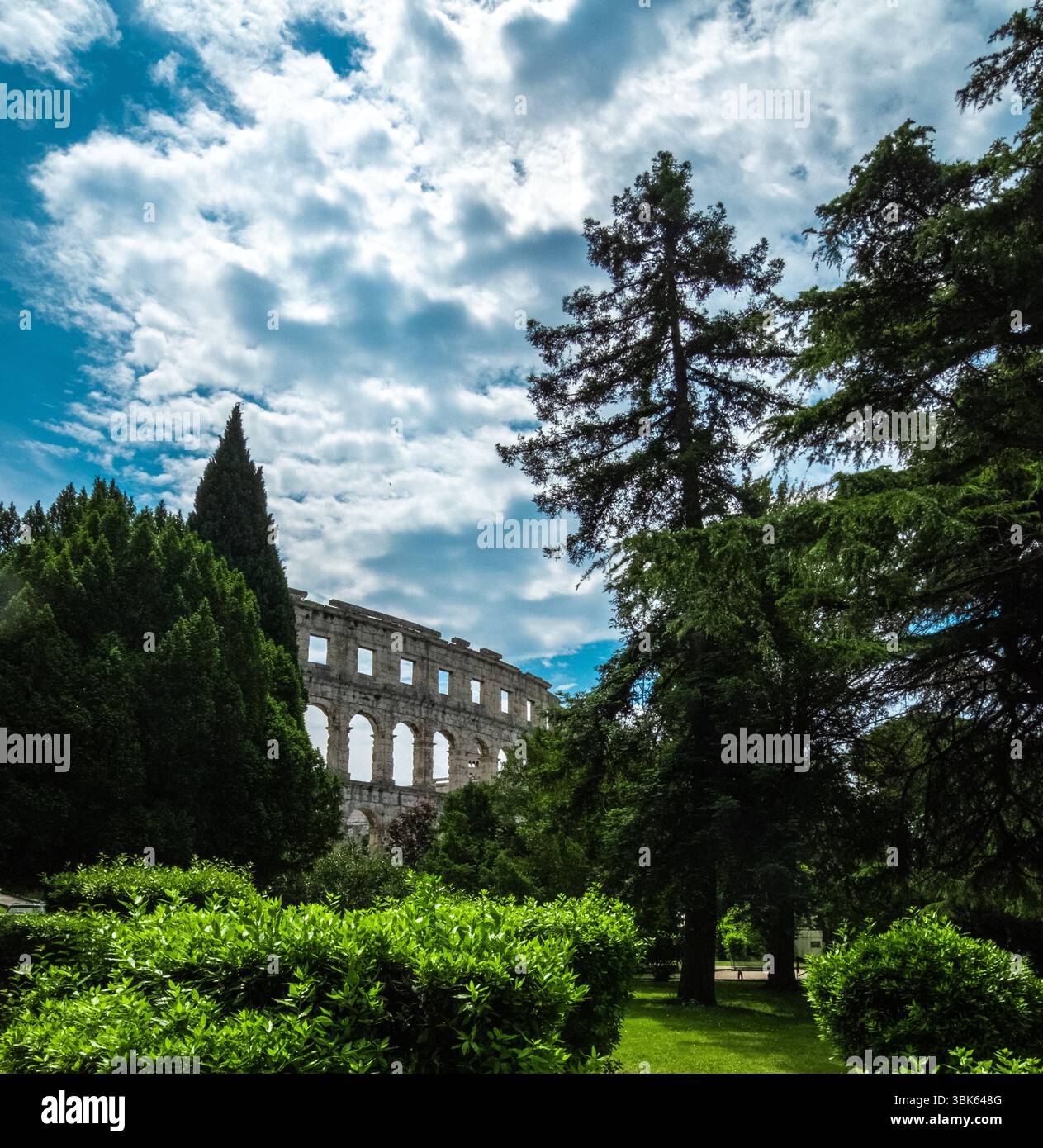 Ancient Roman amphitheater known as Pula Arena seen through green park ...