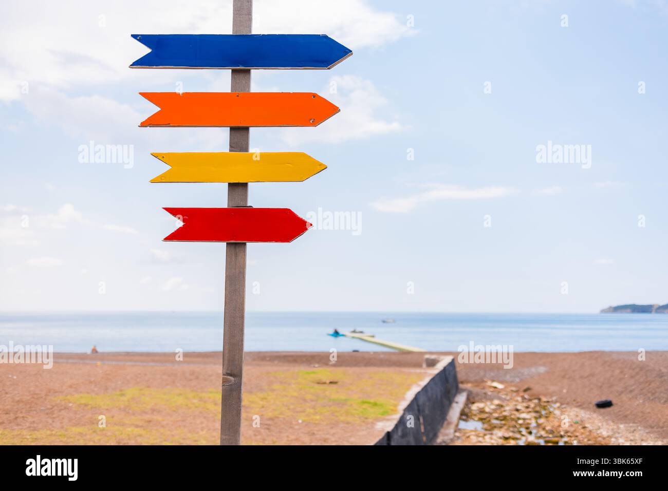 Wooden beach signpost with arrows on seaside promenade, copy space ...