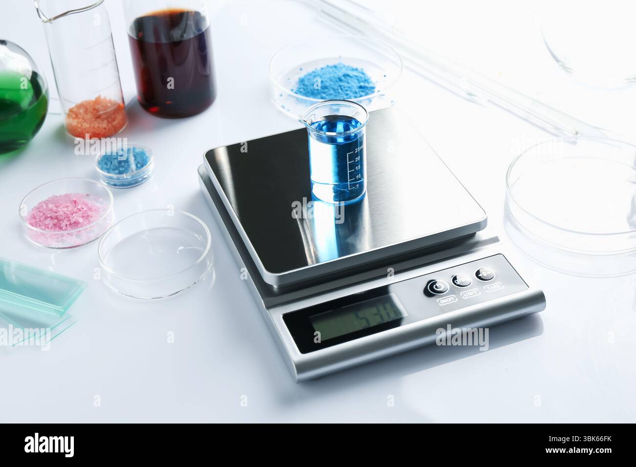 Scale with beaker of sample and other laboratory equipment on white ...