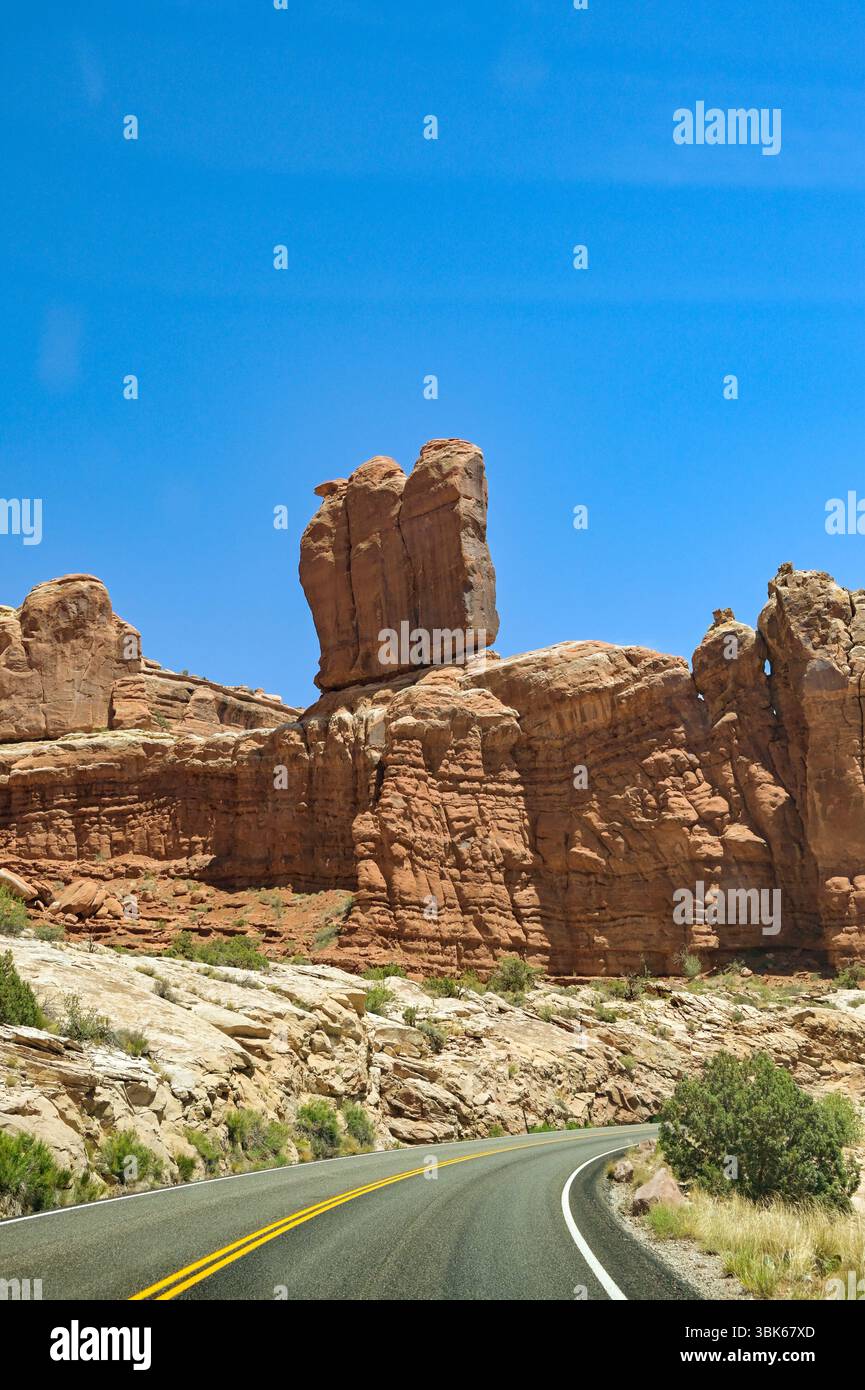 Winding road under tall rock cliffs in the Arches National Park in Moab ...