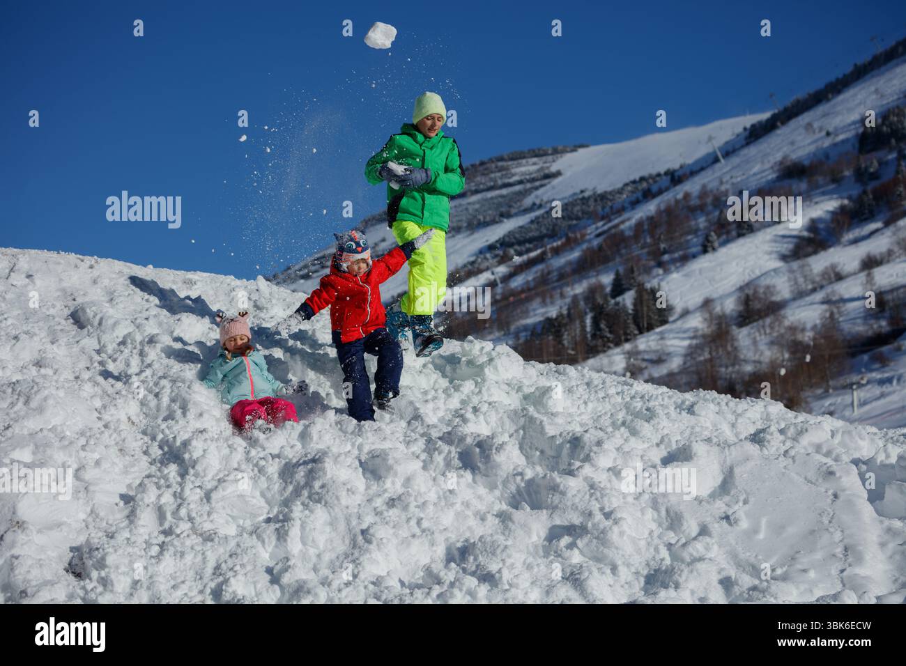 Three sibling have fun snow fighting on mountain slope after ski Stock ...