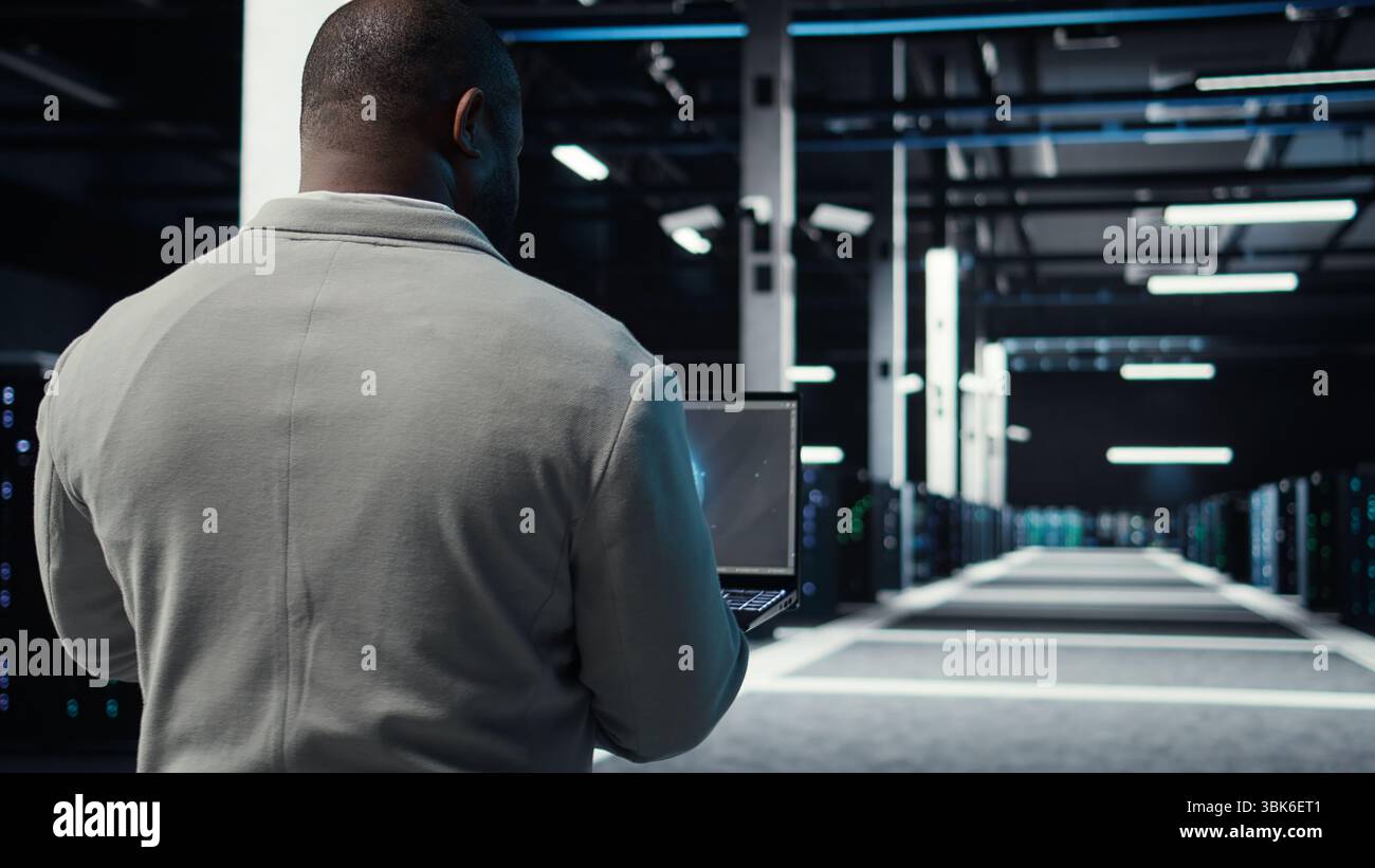 Server room admin using laptop to do infrastructure AI machine learning automatization. Software ...