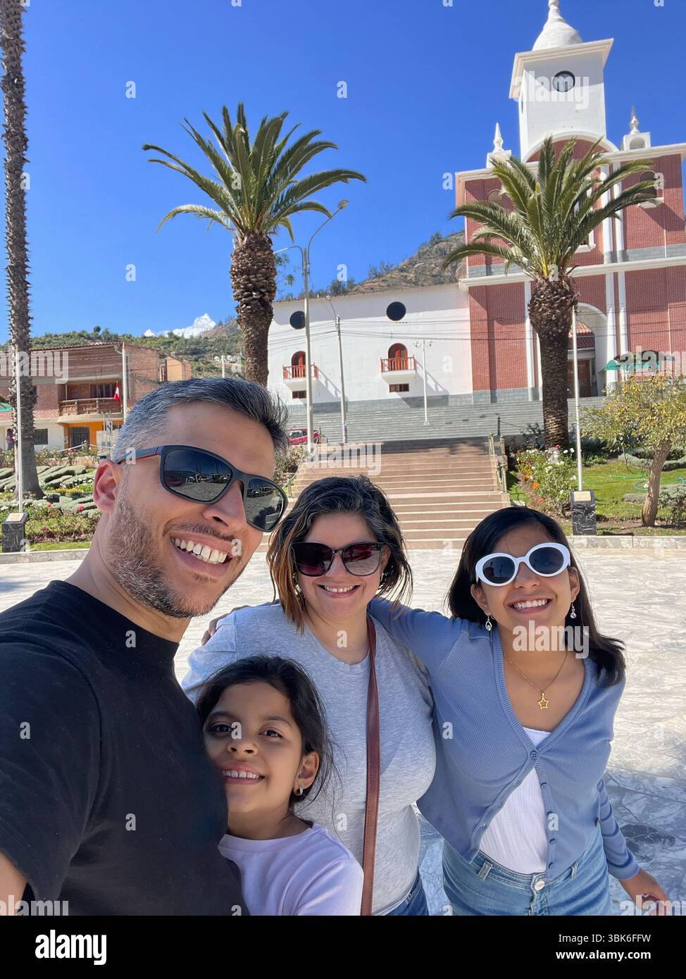 A family of four posing for a picture in front of a church. Scene is ...