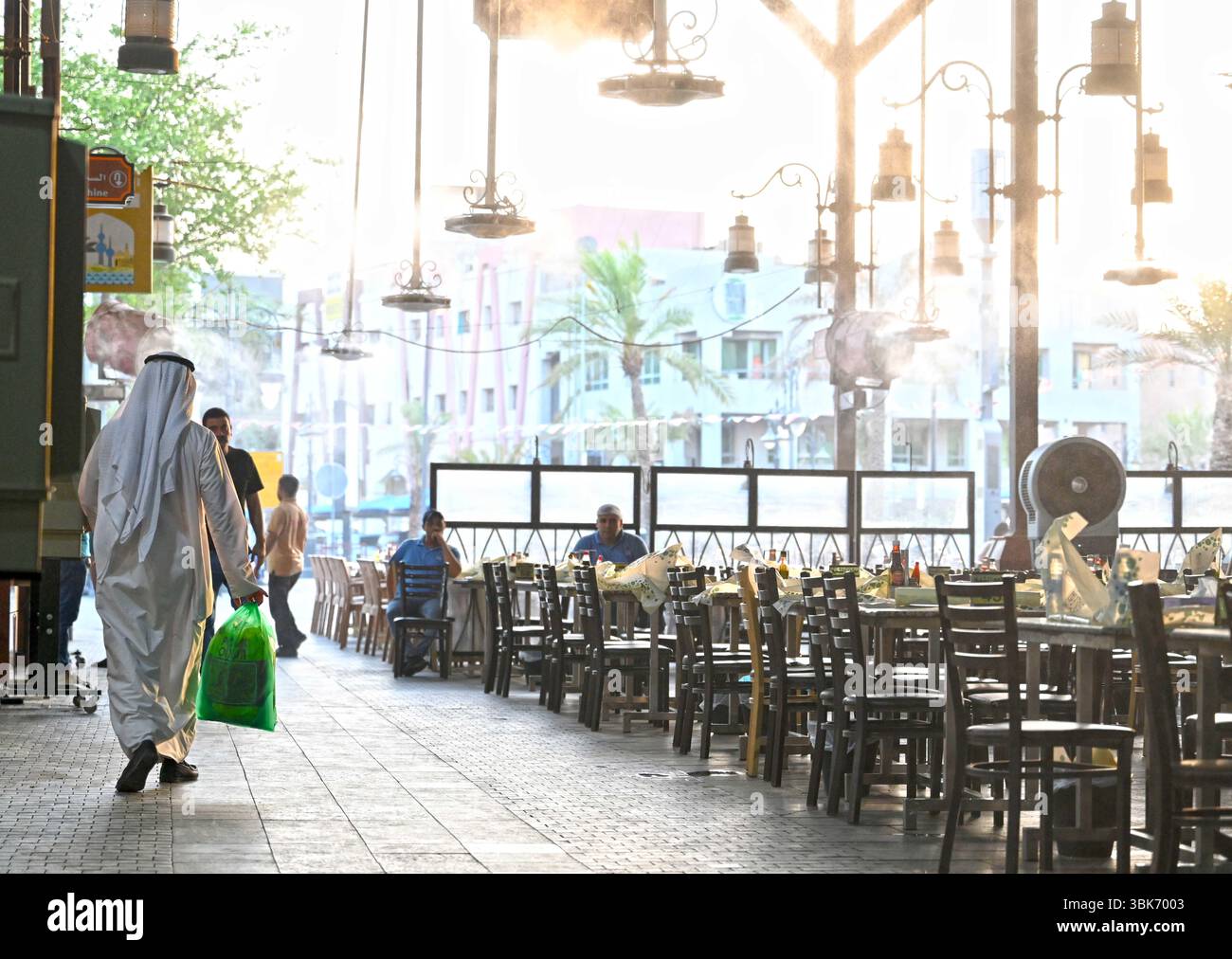 Kuwait City. 18th June, 2025. People walk by electric fans installed ...