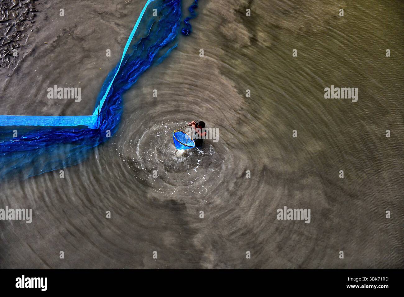 A fisherman seen using colourful nets during fishing on the Matla river ...