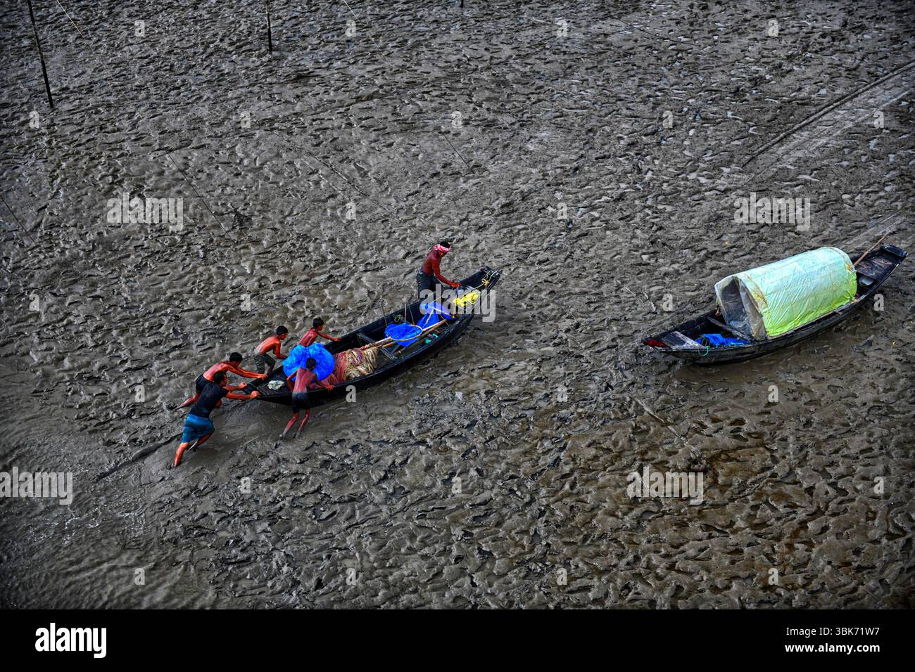 Fishermen seen pushing their boat which got stuck in deep mud on the ...