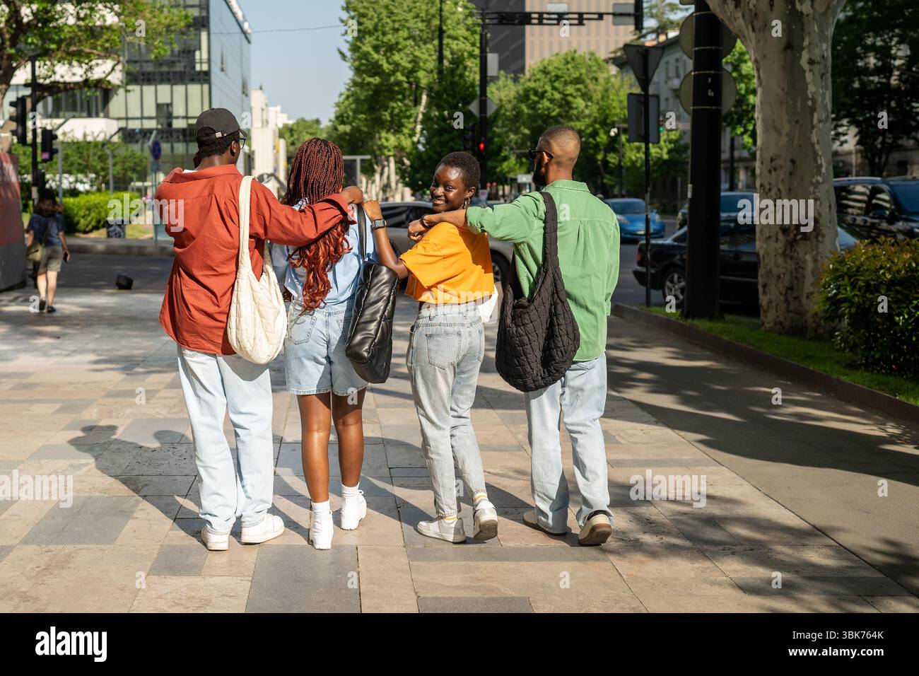 Happy African American friends students hugging walking down street ...