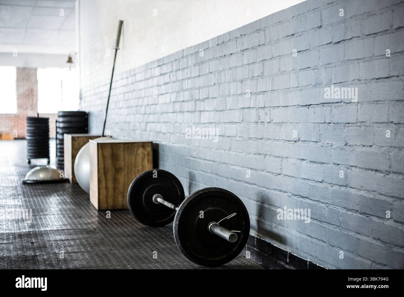 Loaded barbell with weight plates is resting on rubber floor beside ...