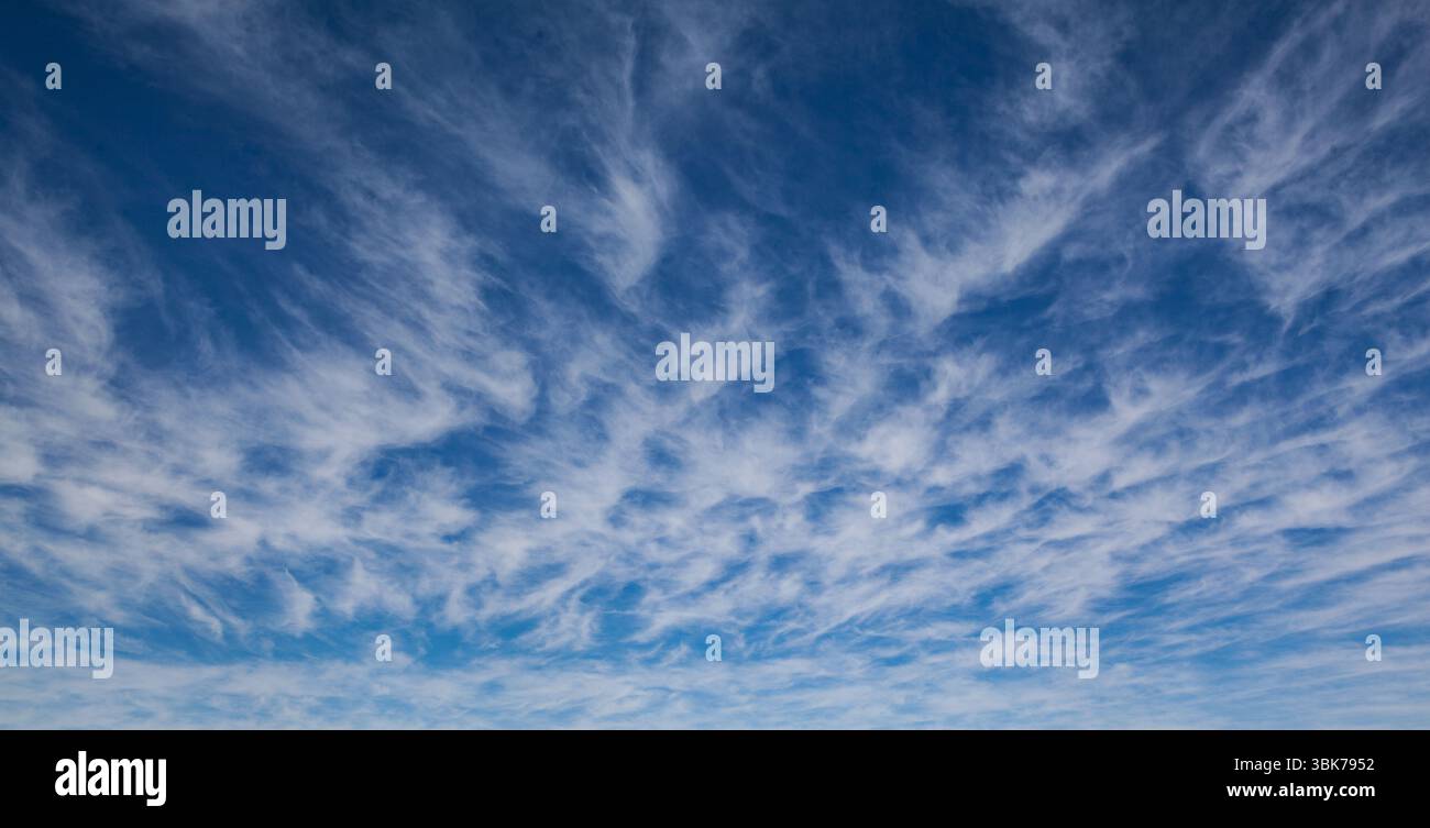 Wispy cirrus clouds are drifting across deep blue sky in flat design ...