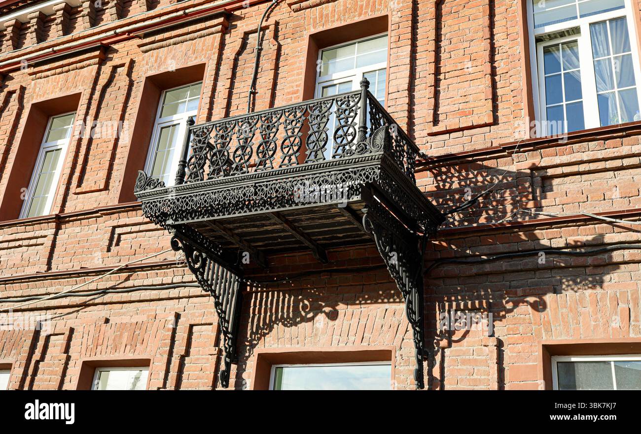 Ornate wrought iron balcony extends from a brick building, highlighting ...