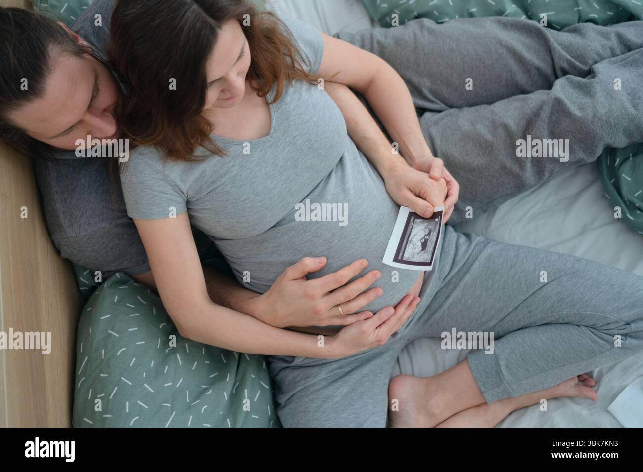 Overhead view of expecting mother in lotus pose holding ultrasound scan ...