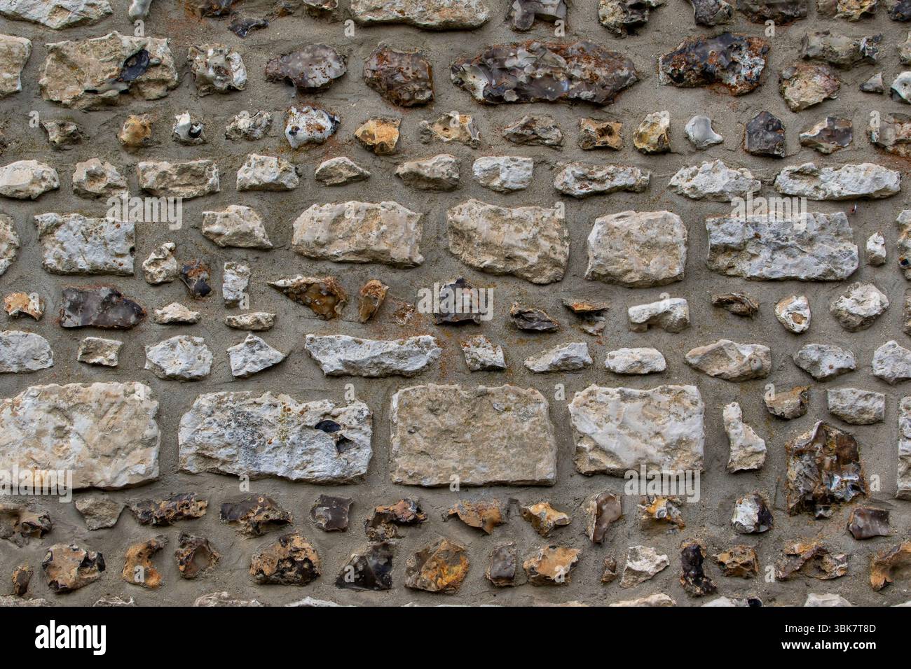 Stone wall facade featuring assorted rock sizes and shapes set in grey ...