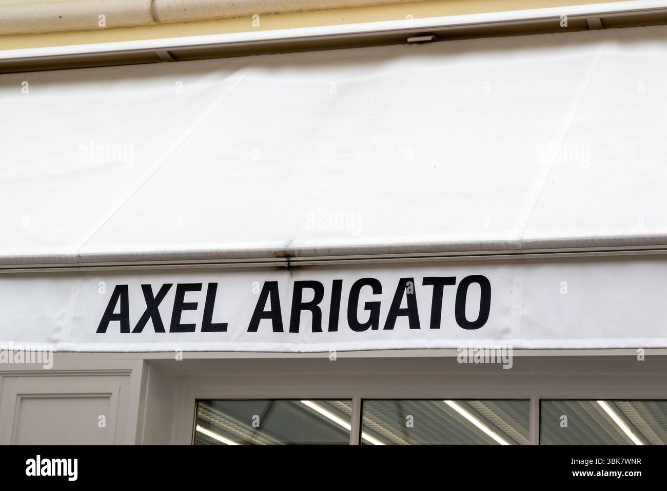 Close-up of an awning with "AXEL ARIGATO" printed on it, above a door ...
