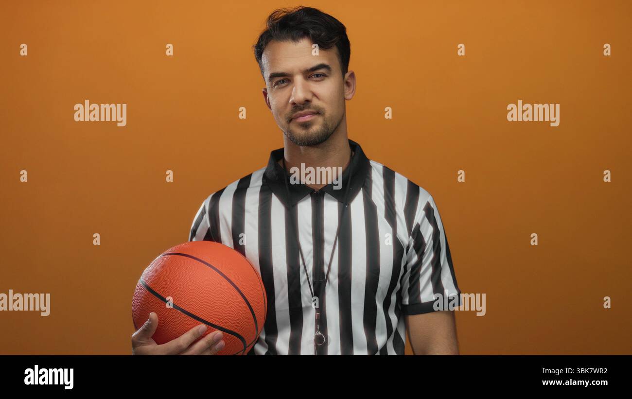 Young hispanic man wearing referee uniform holding basketball against ...