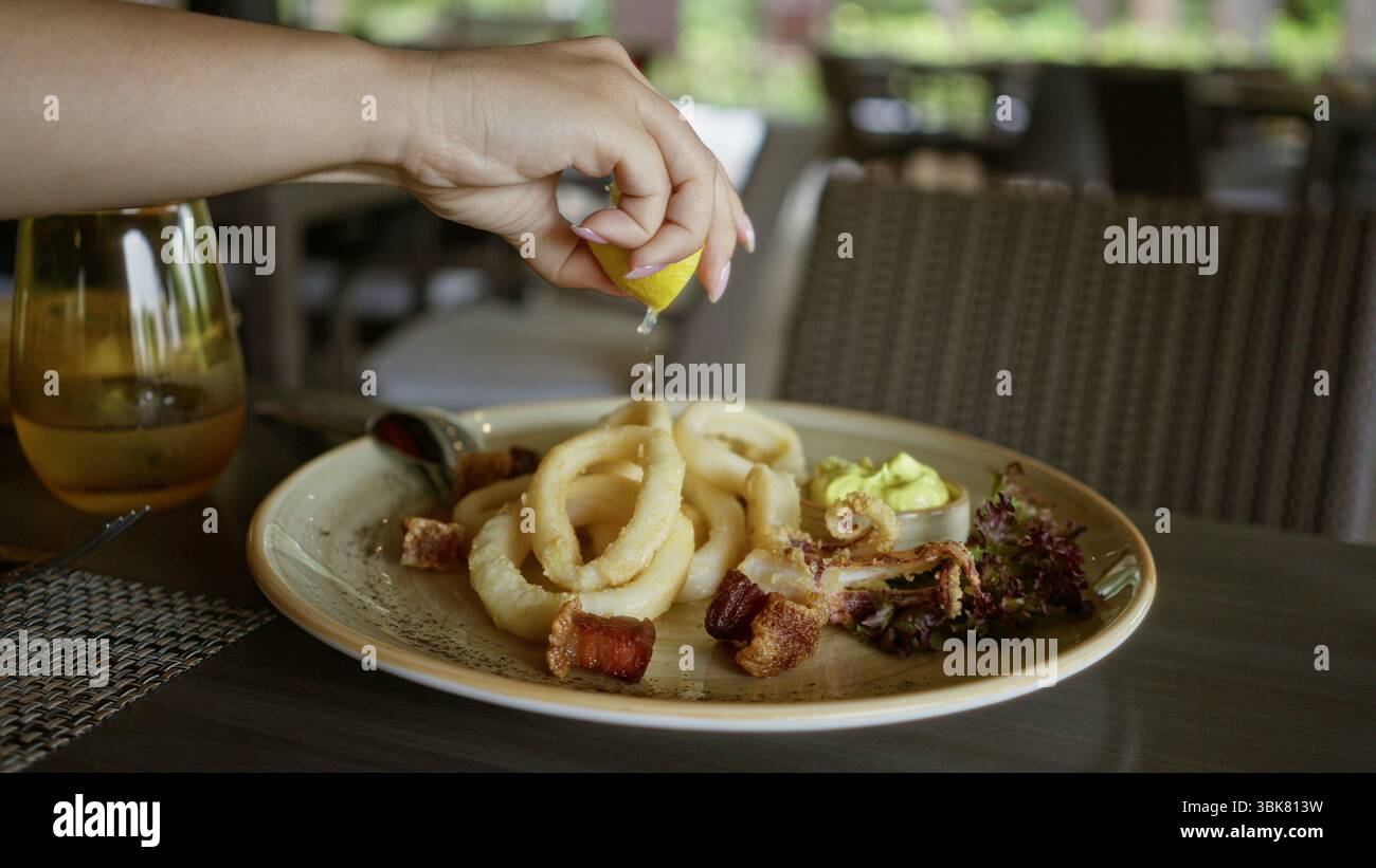 Hand squeezing lemon over fried hi-res stock photography and images - Alamy