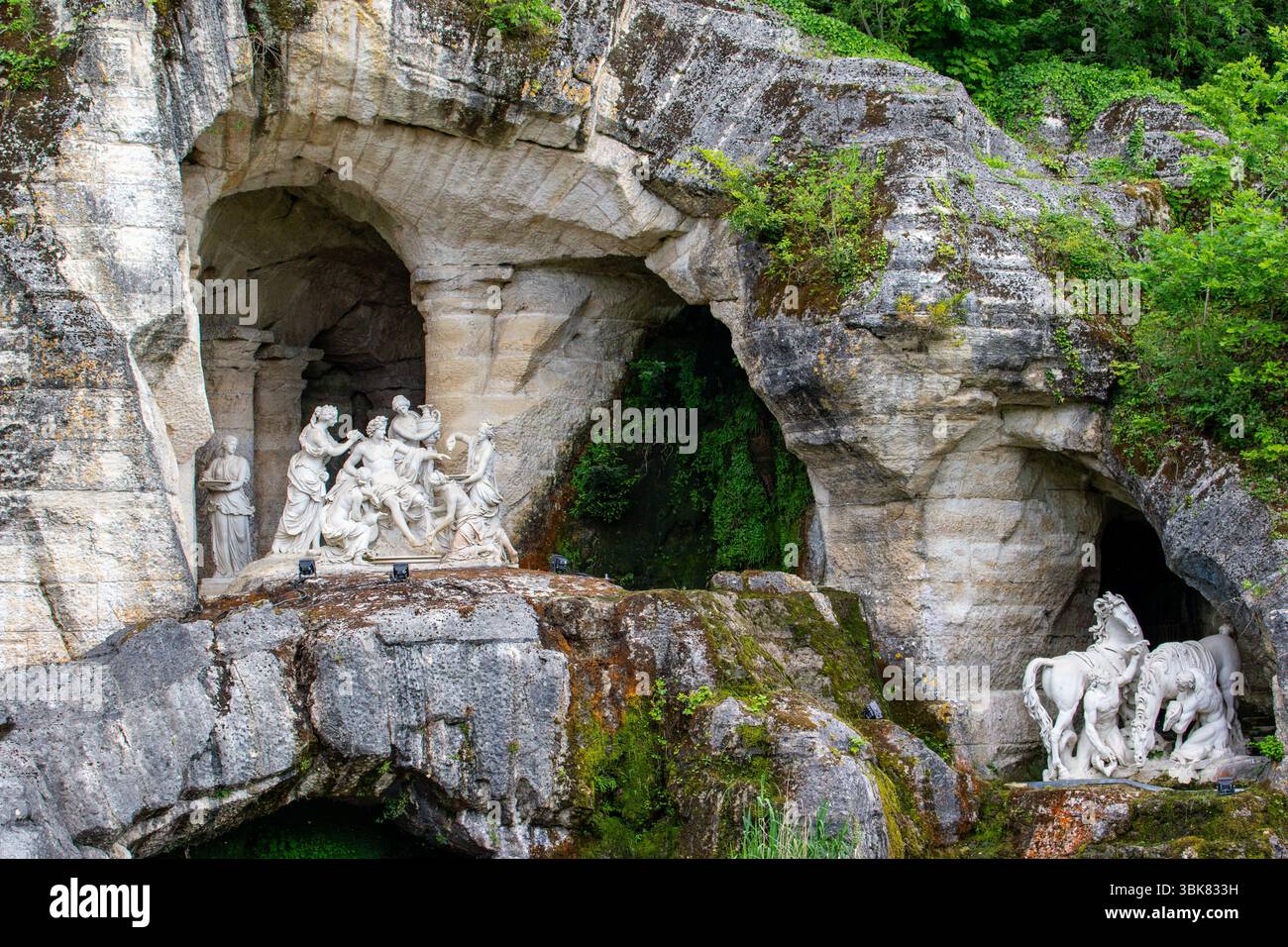 Three grottoes containing white statues carved into rock are covered ...