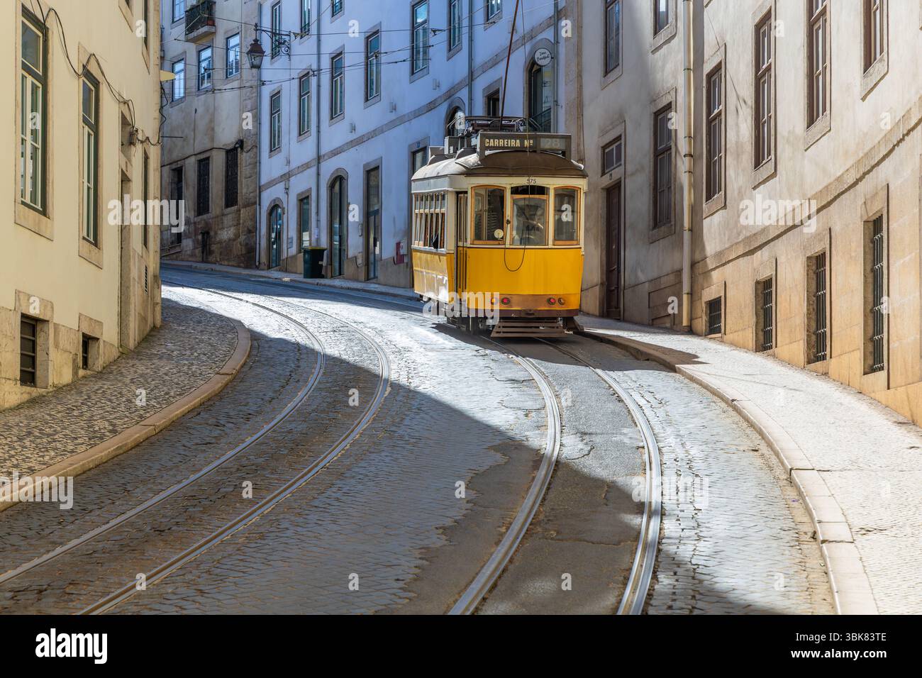 Historic yellow tram climbs a steep cobbled street in Lisbon, Portugal ...