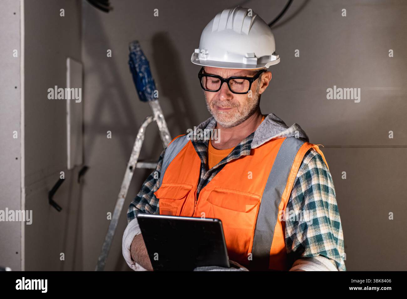 Construction site engineer wearing helmet and safety vest checks ...