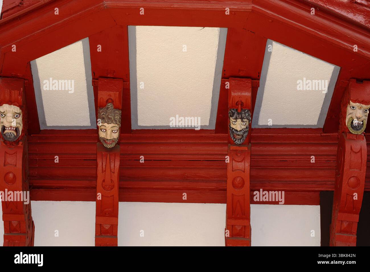 Four bearded grotesque faces grimace and grin from red oak corbels ...