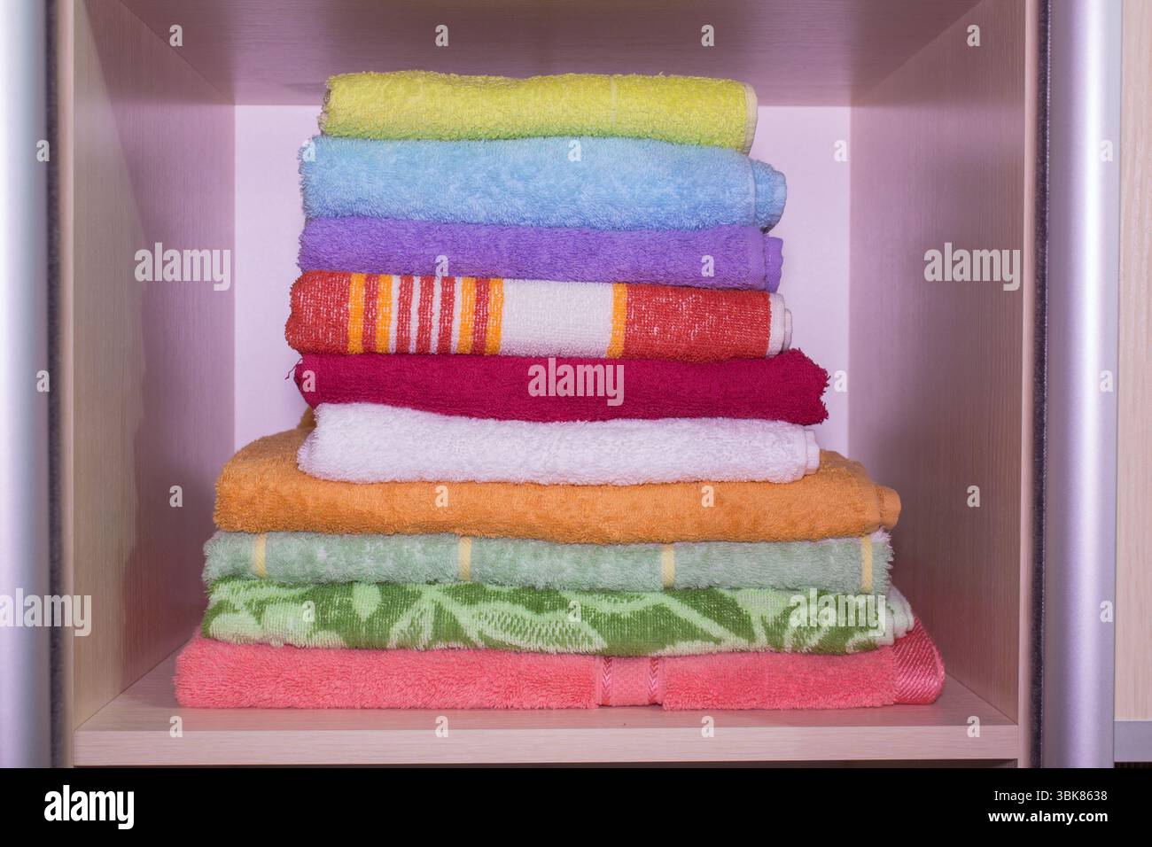 multicolored towels on the shelves in the wardrobe. Stack of towels ...