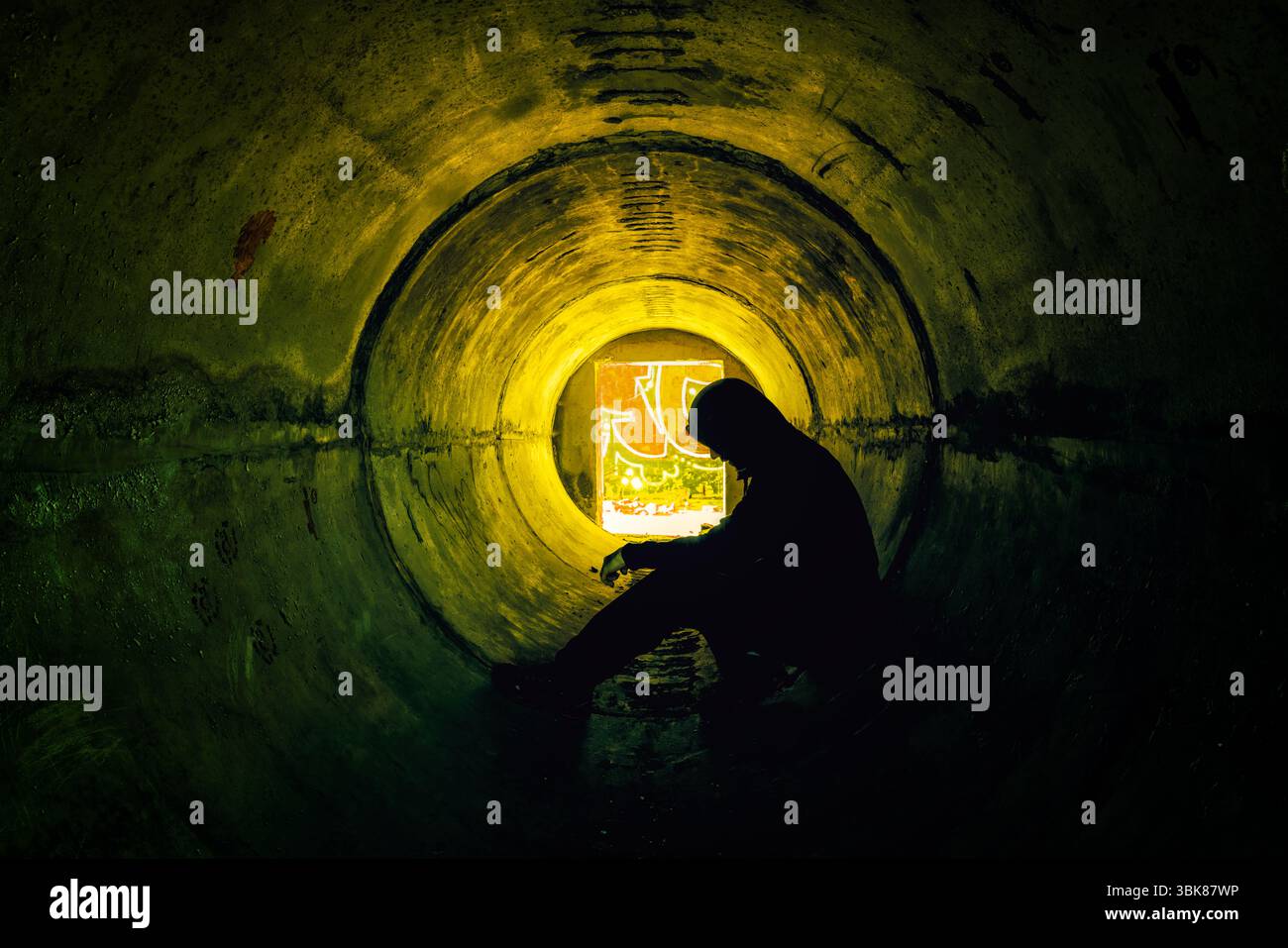 Man sitting in underground concrete tunnel angle shot Stock Photo - Alamy