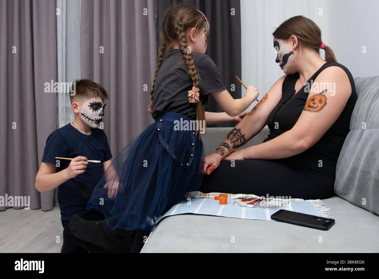 A family enjoys a creative Halloween activity. Two children ...