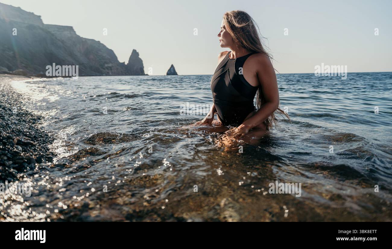 Woman in Black Bathing Suit Sitting in the Ocean Stock Photo - Alamy