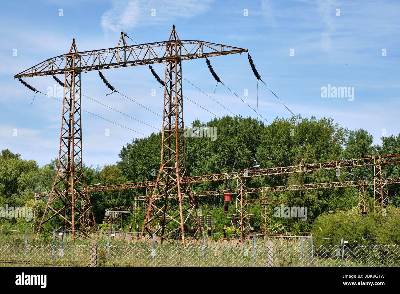 Old rusted high voltage pylons and insulators at disused power station ...