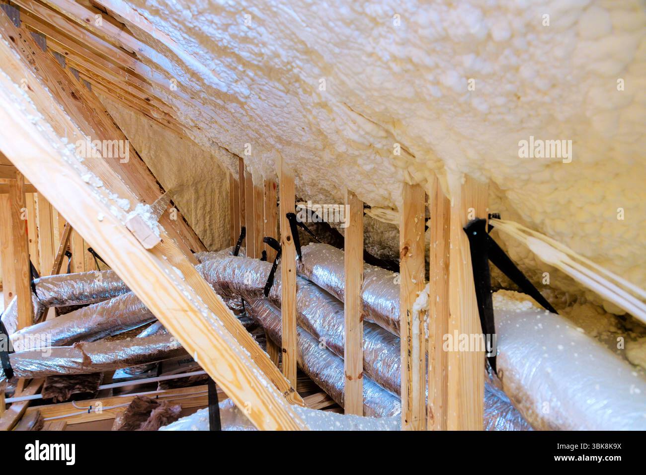 Workers are installing insulation in an attic, wooden beams ductwork ...