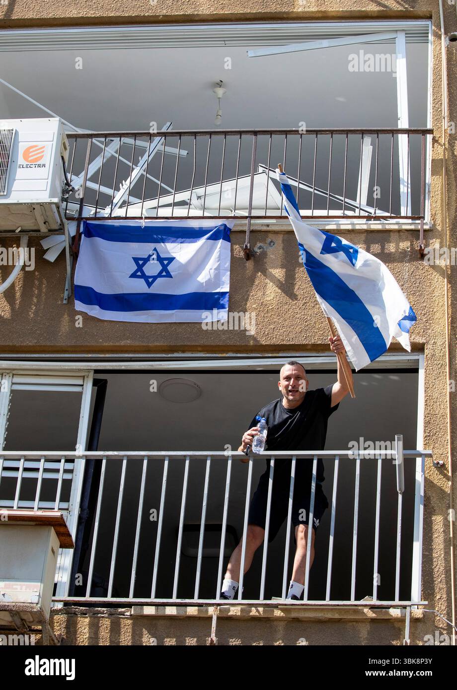 Holon, Israel. 19th June, 2025. An Israeli waves the flag from his ...