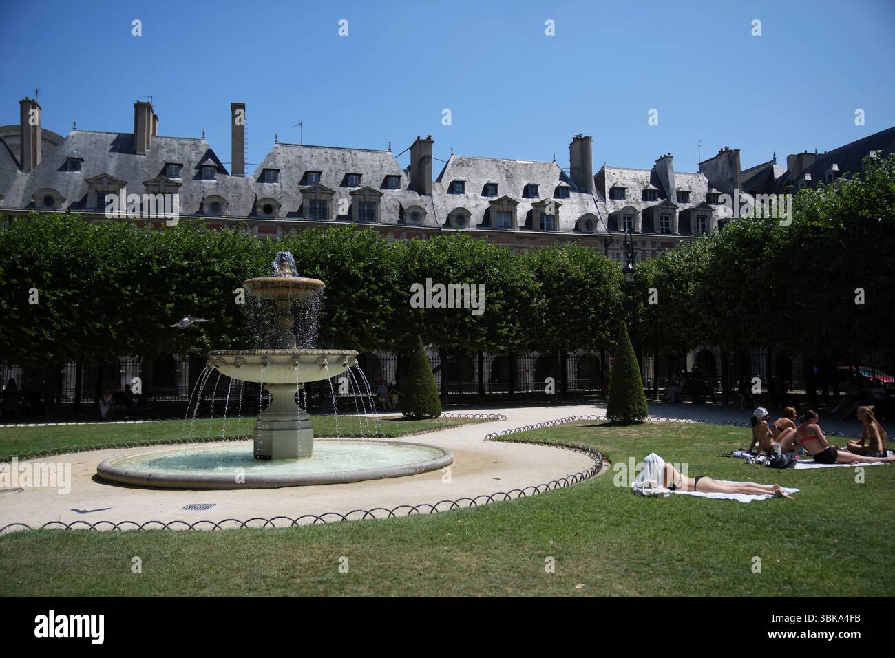 People sunbathe near a fountain as temperature rose up to 32 degrees ...