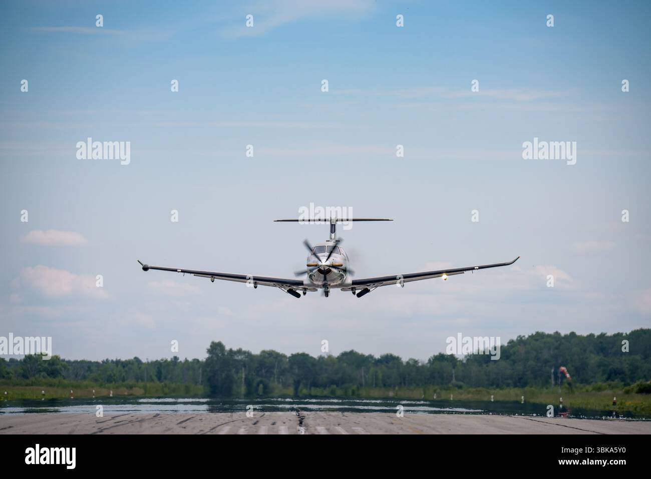 Single-engine turbo-prop aircraft ascending after rotation, gear coming ...