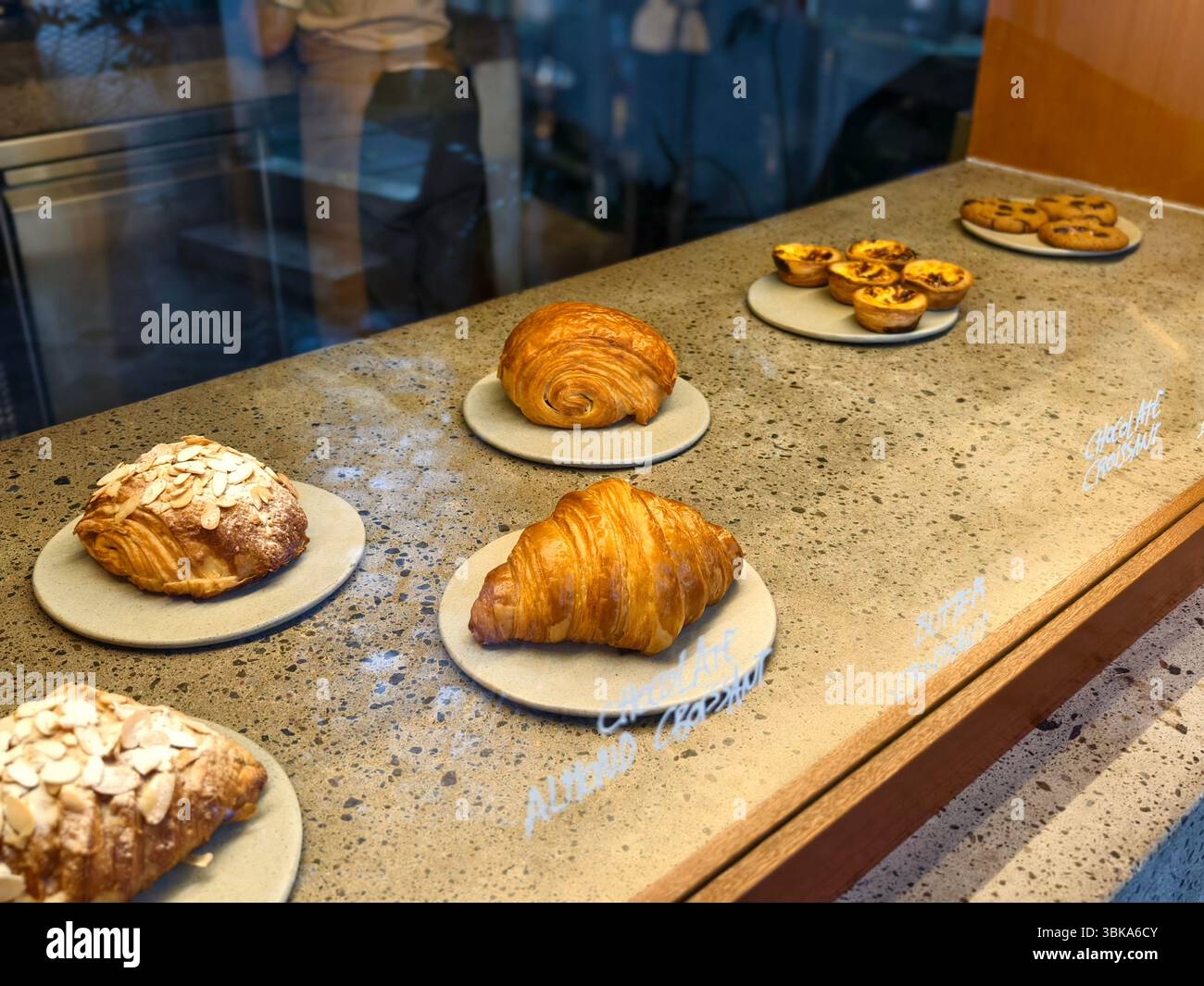 A bakery display featuring an assortment of croissants, almond pastries, Portuguese egg tarts ...