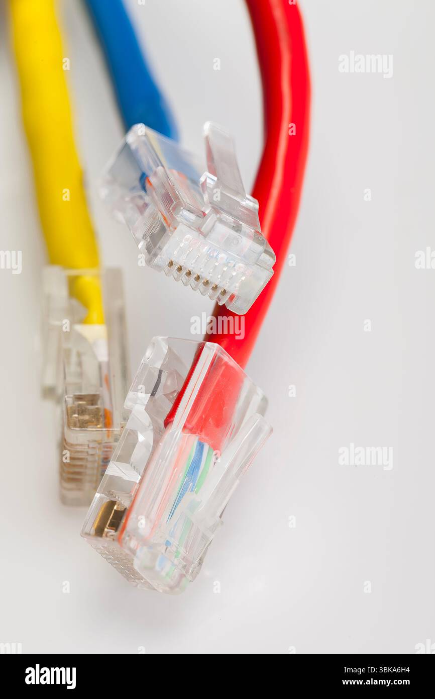 Three Ethernet cables in red, blue, and yellow lie side by side against ...