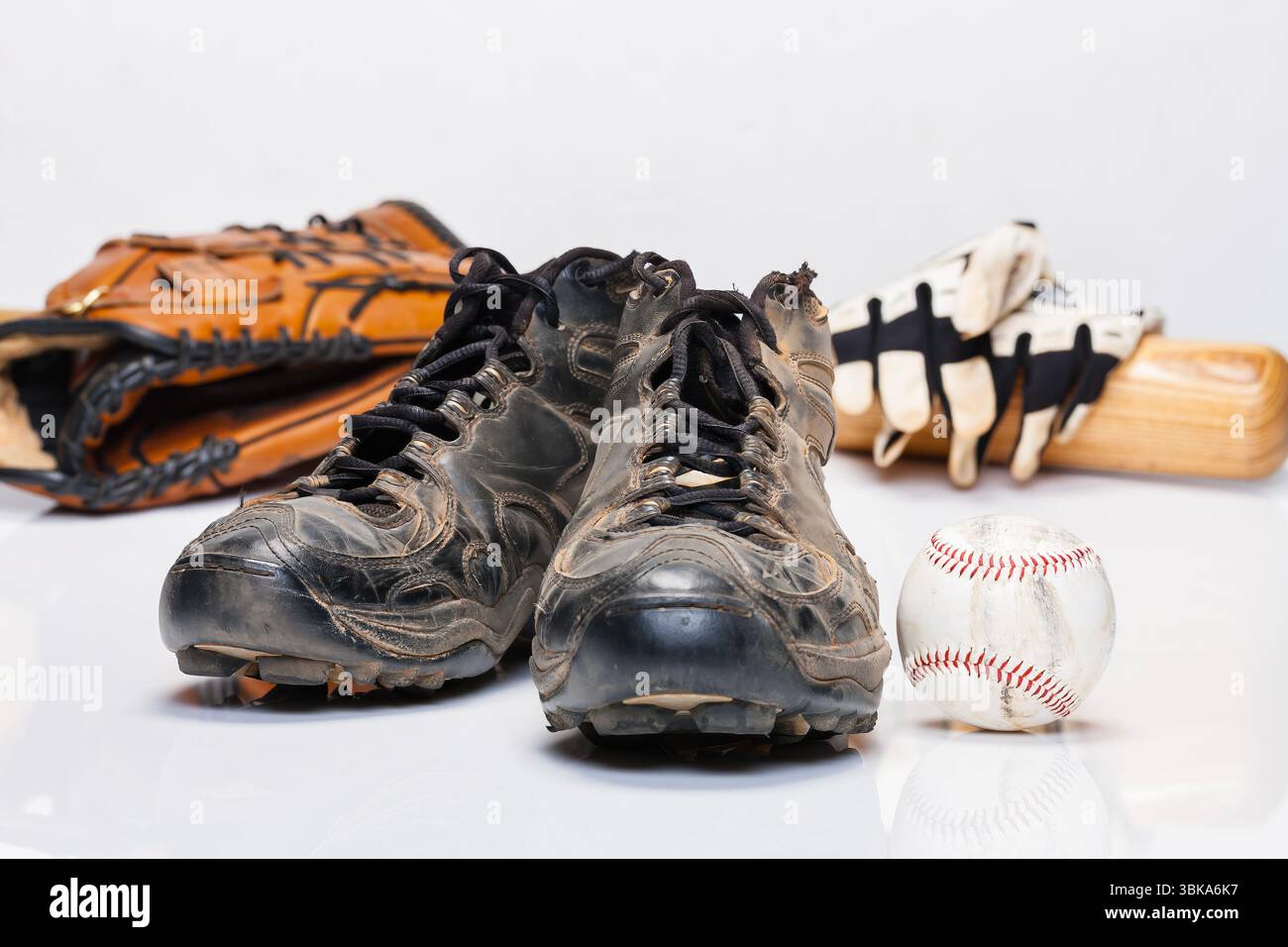 A worn-out pair of dirty baseball cleats sit in a studio setting with a ...