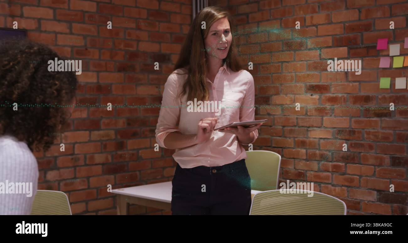 Presenting woman in pink blouse using tablet in meeting area, with ...