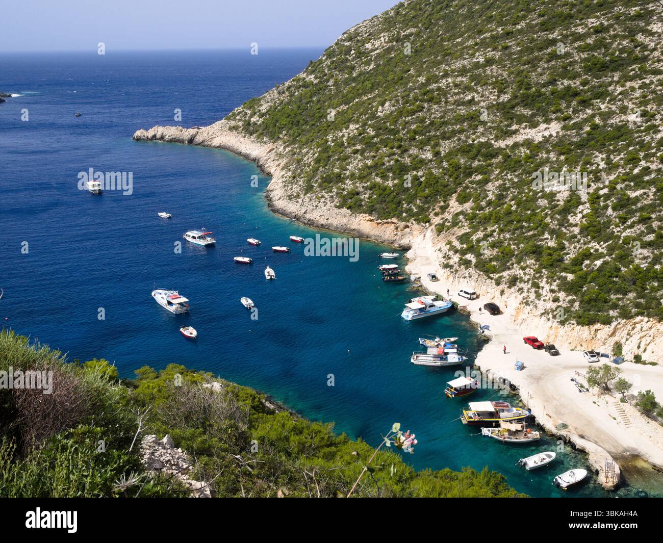 Aerial view of Limnionas Port, Zakynthos island, Greece, with boats in deep blue water and lush ...