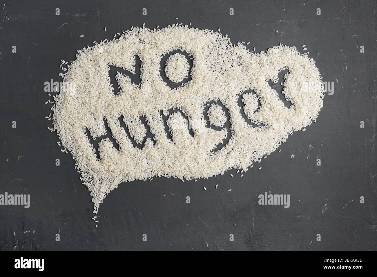 No Hunger text written on a rice scattered on a dark table. Food crisis ...