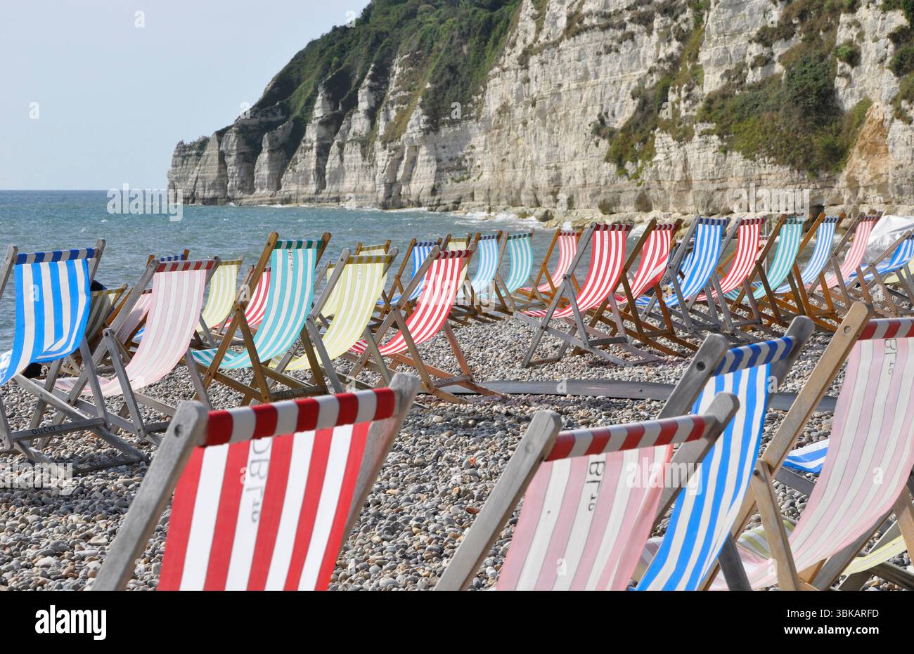 Deckchairs lined up on the pebble beach at Beer in Devon looking ...