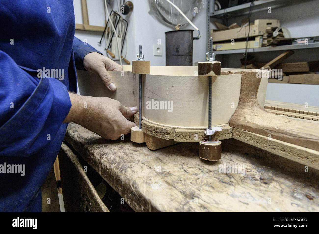 Artisan clamps and aligns guitar side to body mold during building ...