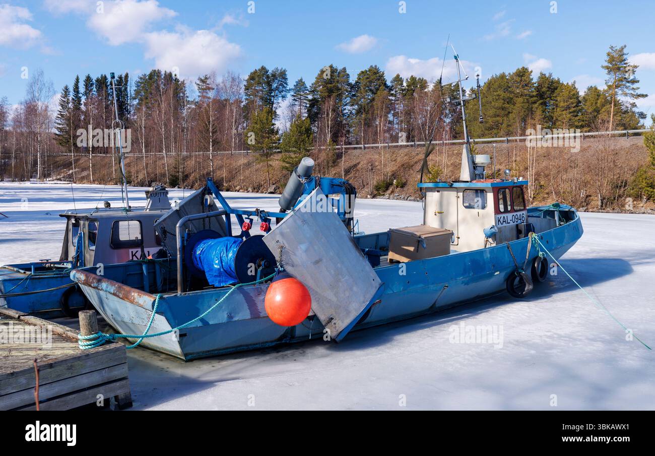 Small inland fishing trawlers anchored and stuck in ice at Spring at Kivisalmi marina, Lake ...