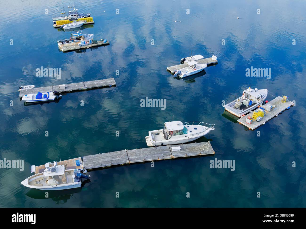 Small boats are moored to floating docks on a calm blue body of water ...