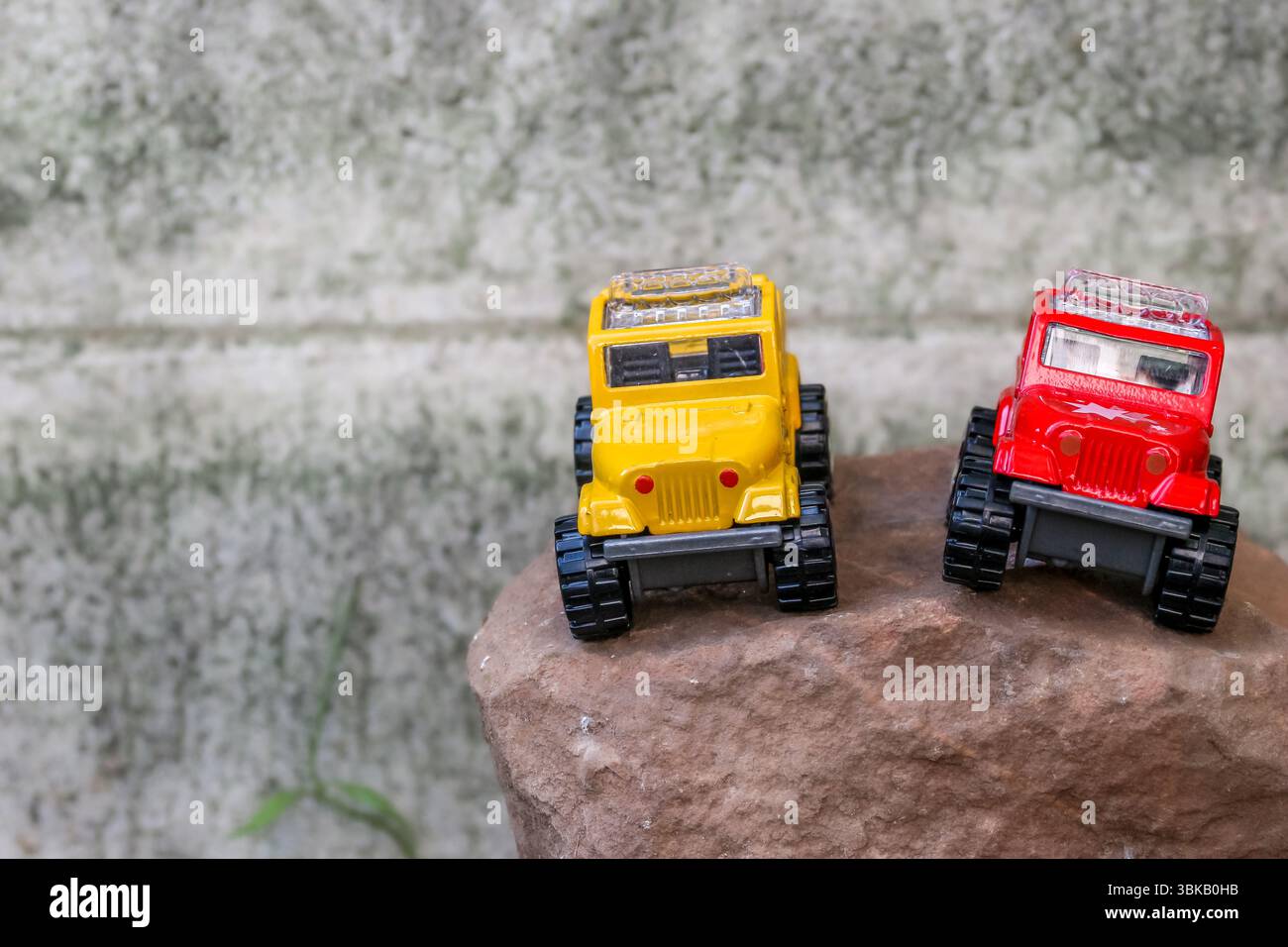 Miniature red and yellow 4x4 pickup trucks parked on rocky terrain ...
