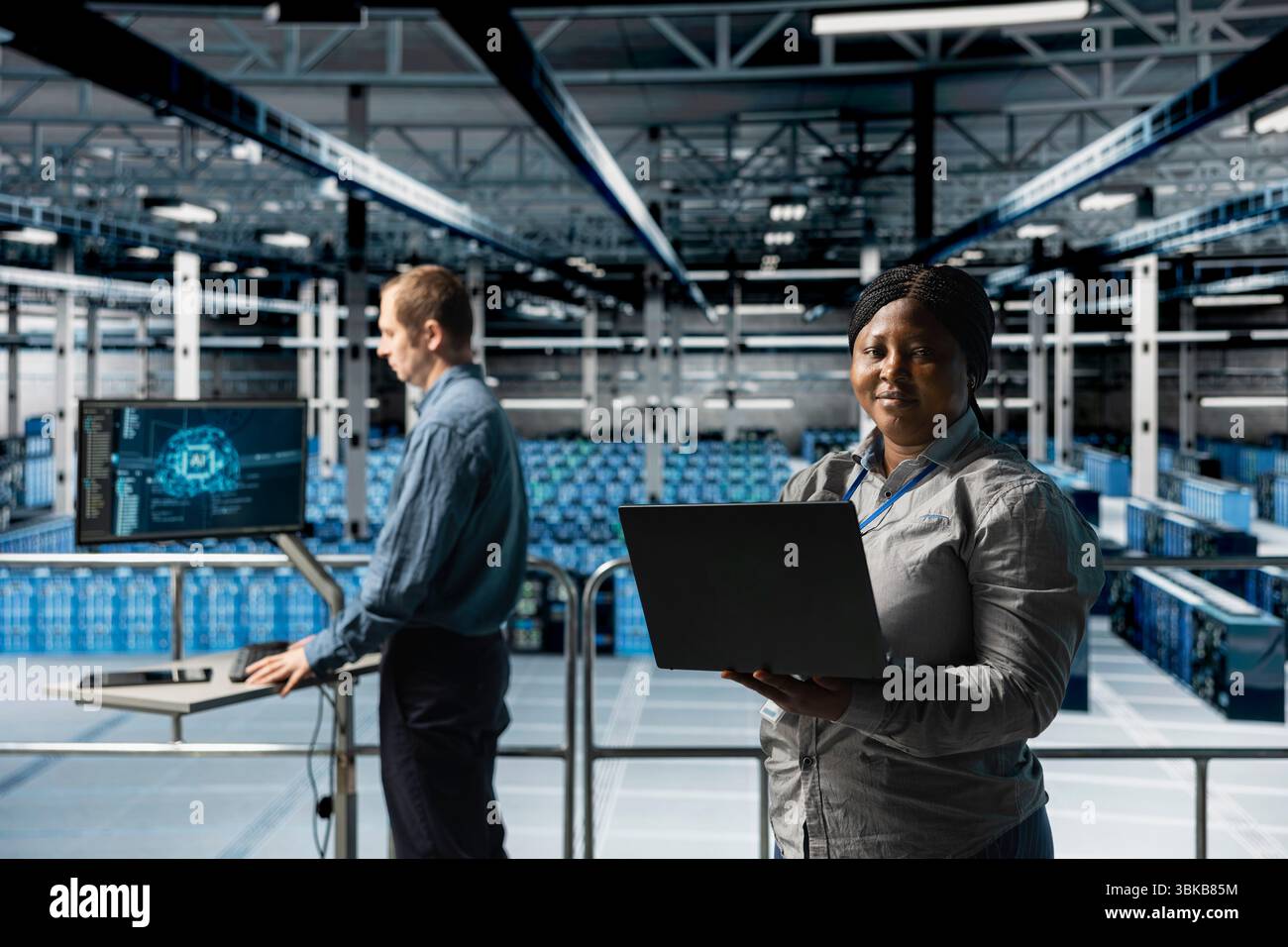 Portrait of smiling female engineer in server farm next to colleague doing infrastructure AI ...