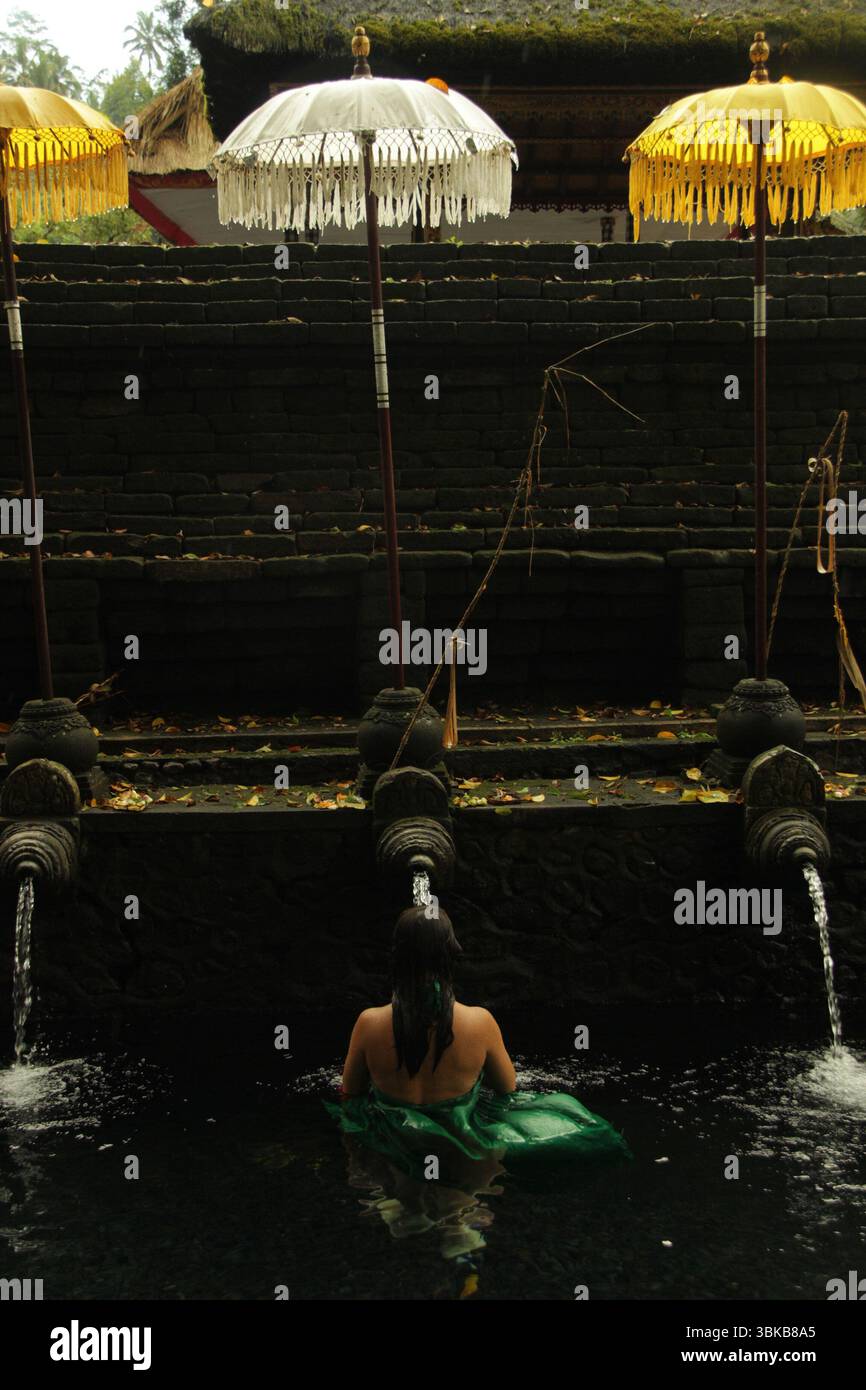 Spiritual ritual, sacred water, temple in Bali — A woman performs a ...