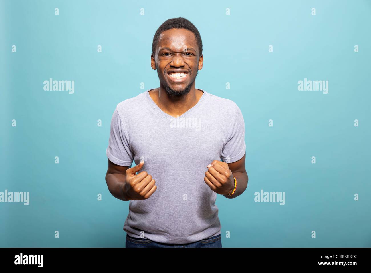 Cheerful young man raising his fist, feeling empowered and confident ...
