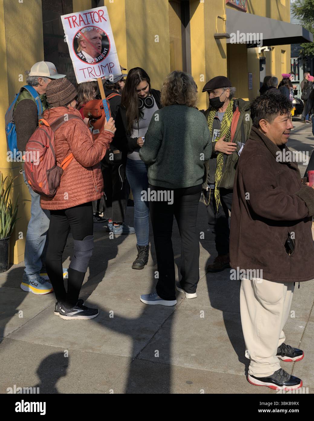 Protestors stand on the street and hold a "Traitor Trump" sign. Photo ...