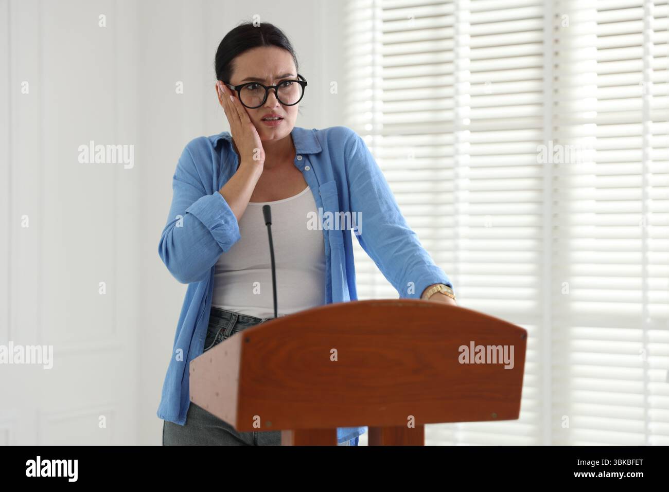 Fear of public speaking. Nervous woman with microphone at lectern ...